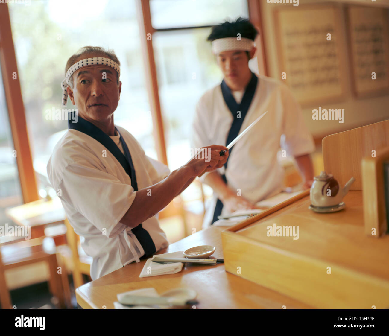 Two Japanese chefs preparing for diners in a traditional restaurant ...