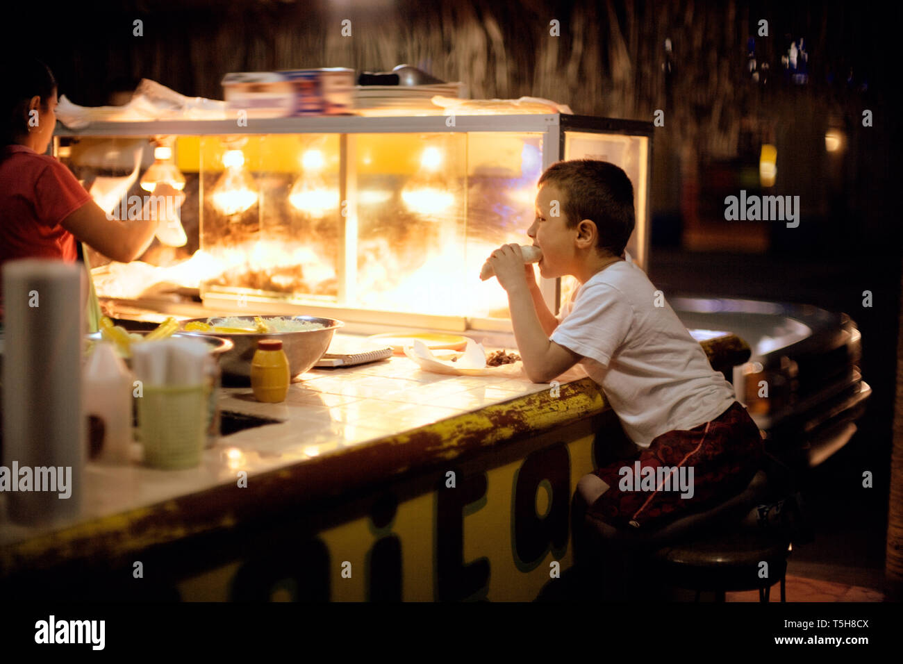 Side view of a boy eating food in a stall Stock Photo - Alamy
