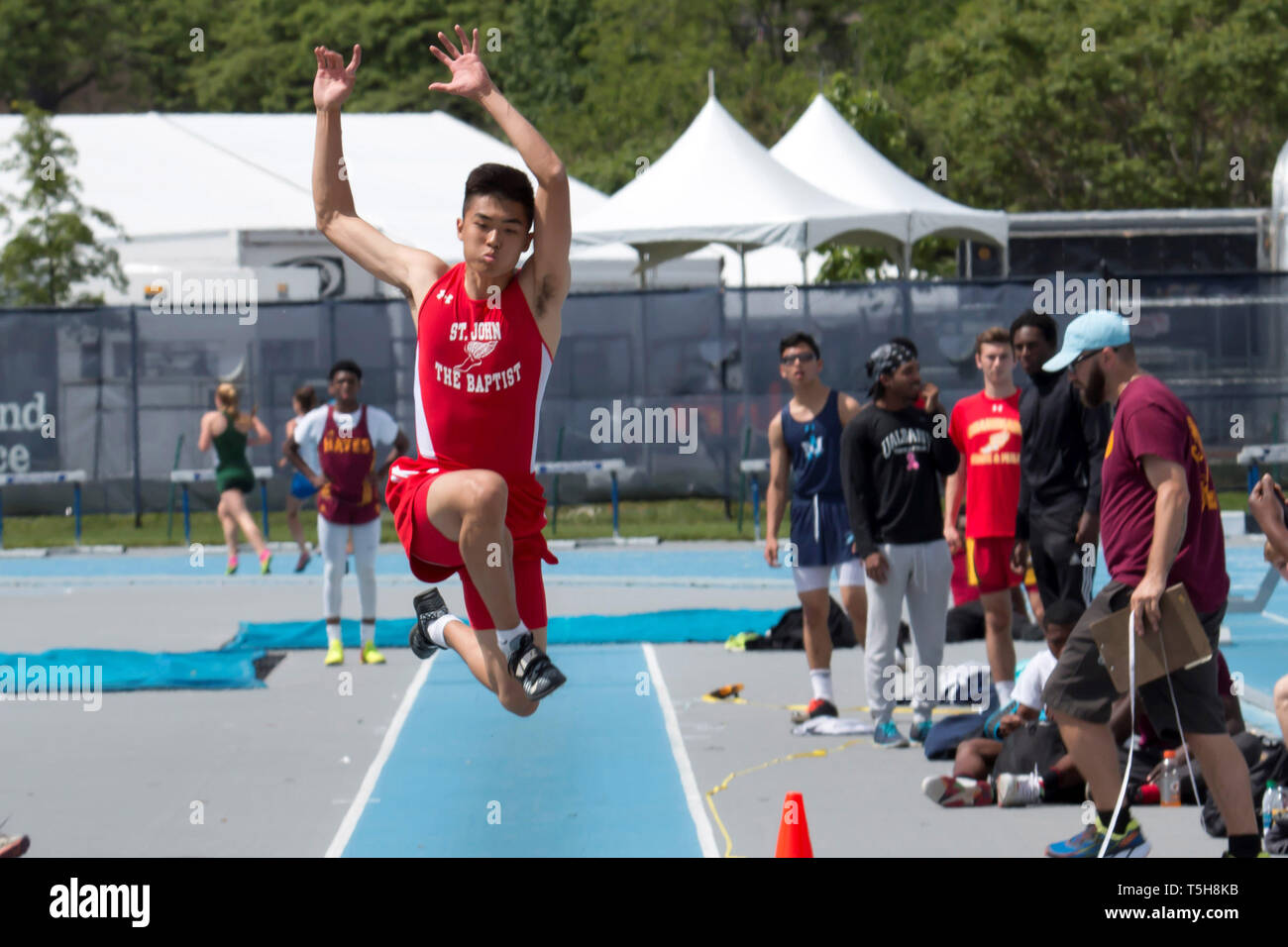 A male high school athlete triple jumps during the CHSAA Catholic State ...