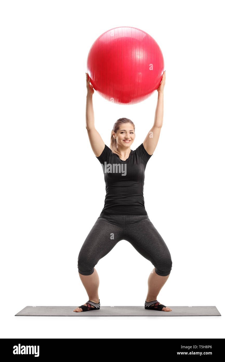 Full length portrait of a young female lifting a fitness ball on an ...