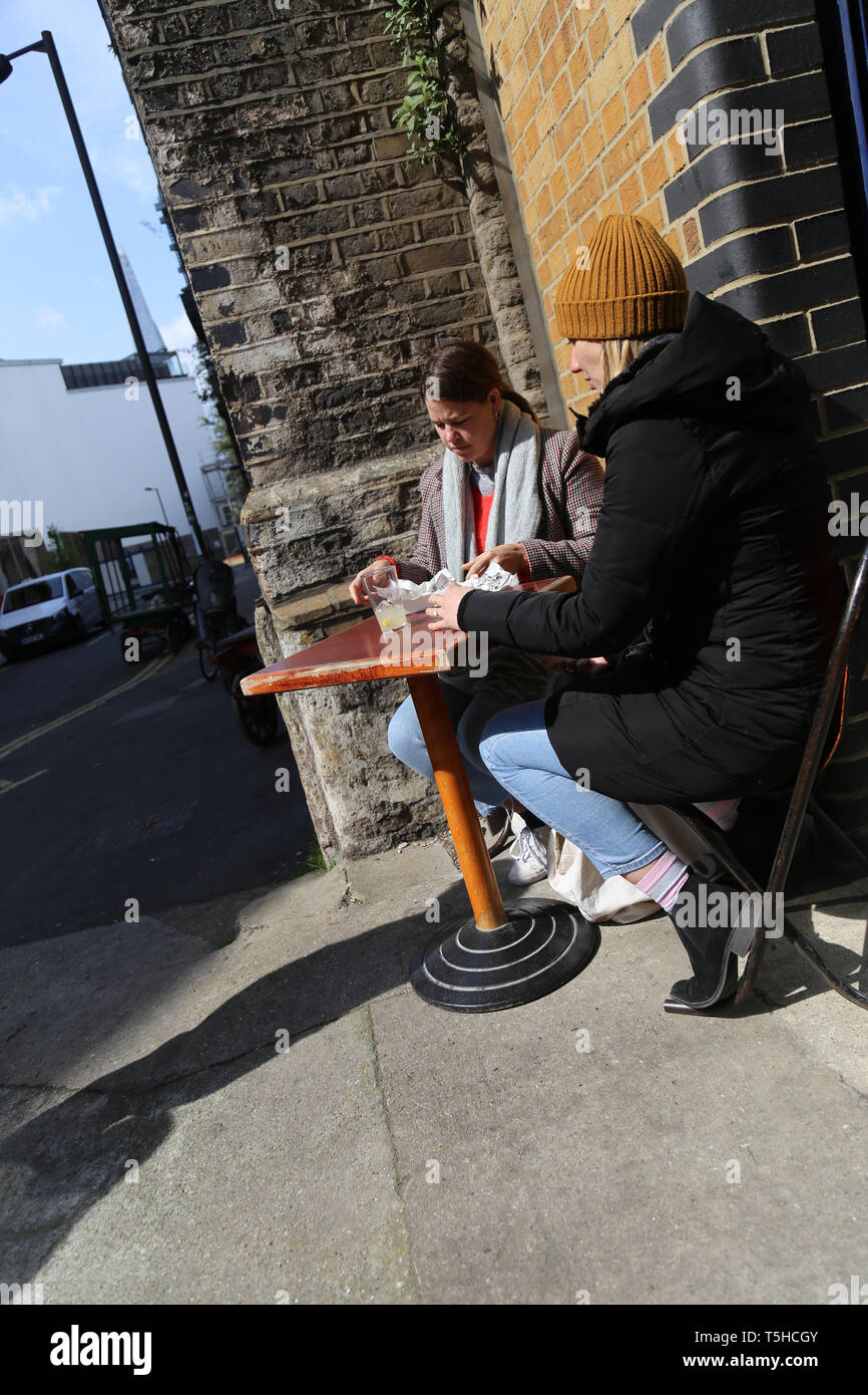 two woman eating seated in a table in a street food road. Rope walk ...