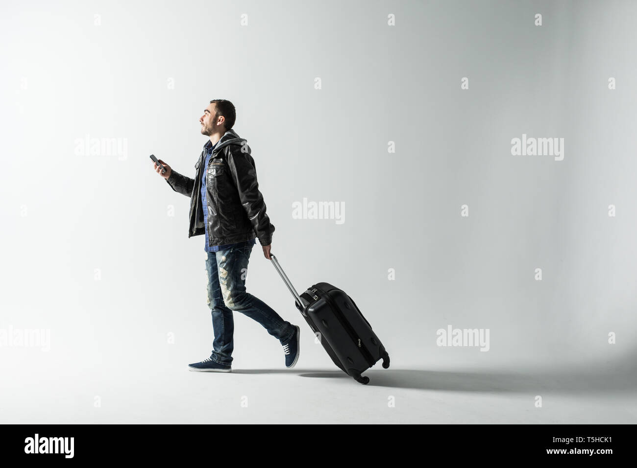 Side view of traveler man holding suitcase posing over white background ...