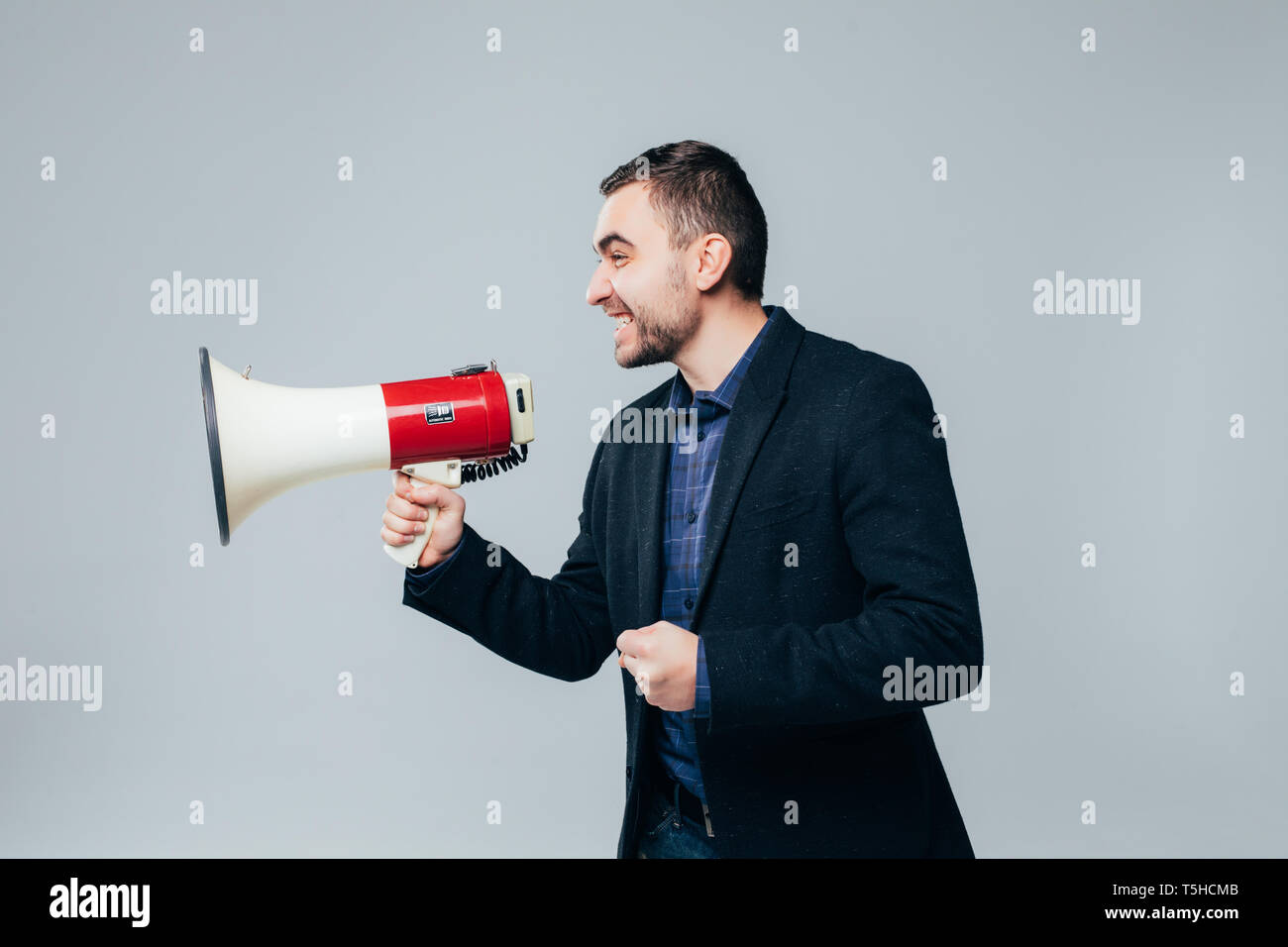 portrait of young man shouting with megaphone against a white ...