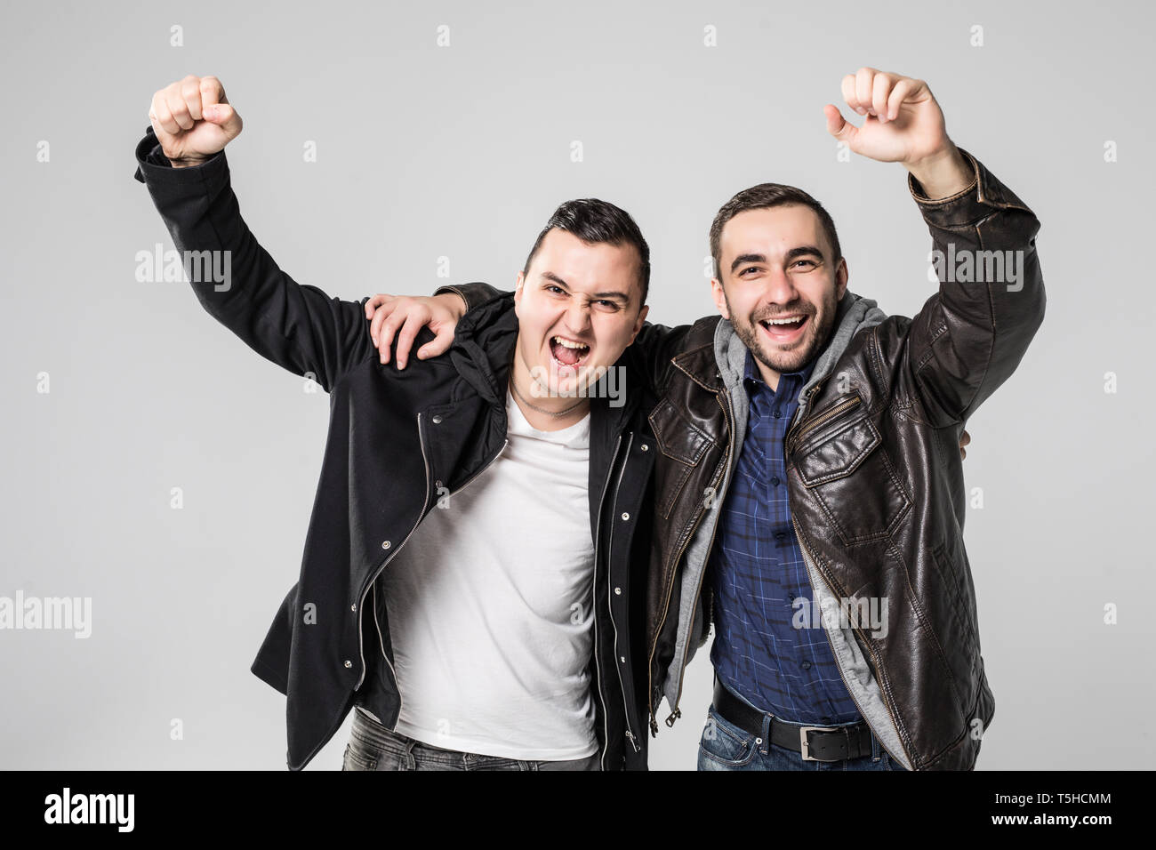Portrait of two cheerful young men celebrating isolated over white ...