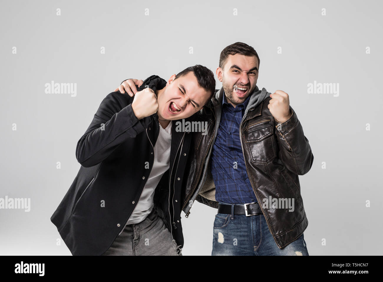 Portrait of two cheerful young men celebrating isolated over white ...