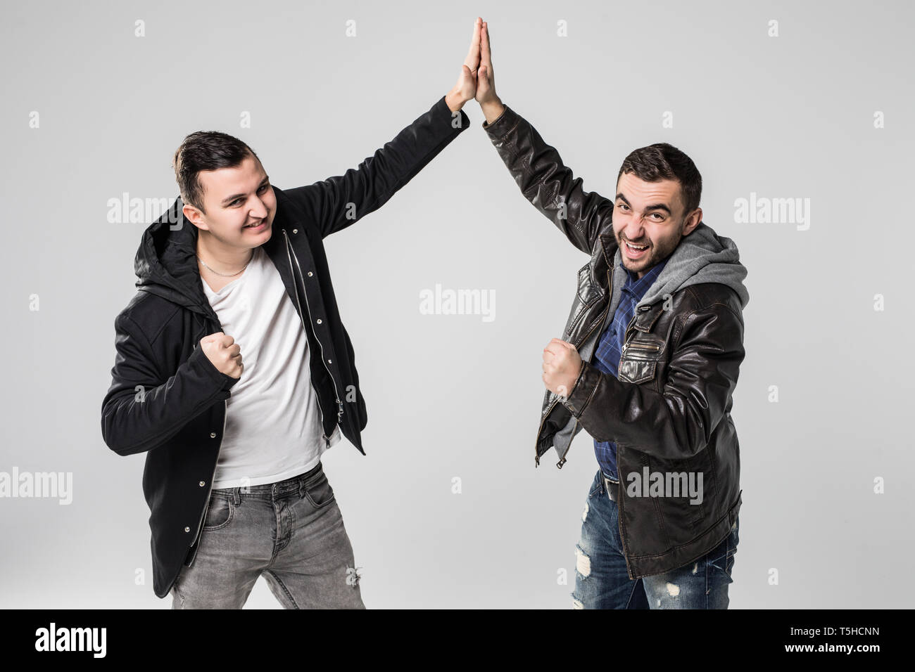 Full length portrait of two happy young men giving high five isolated ...