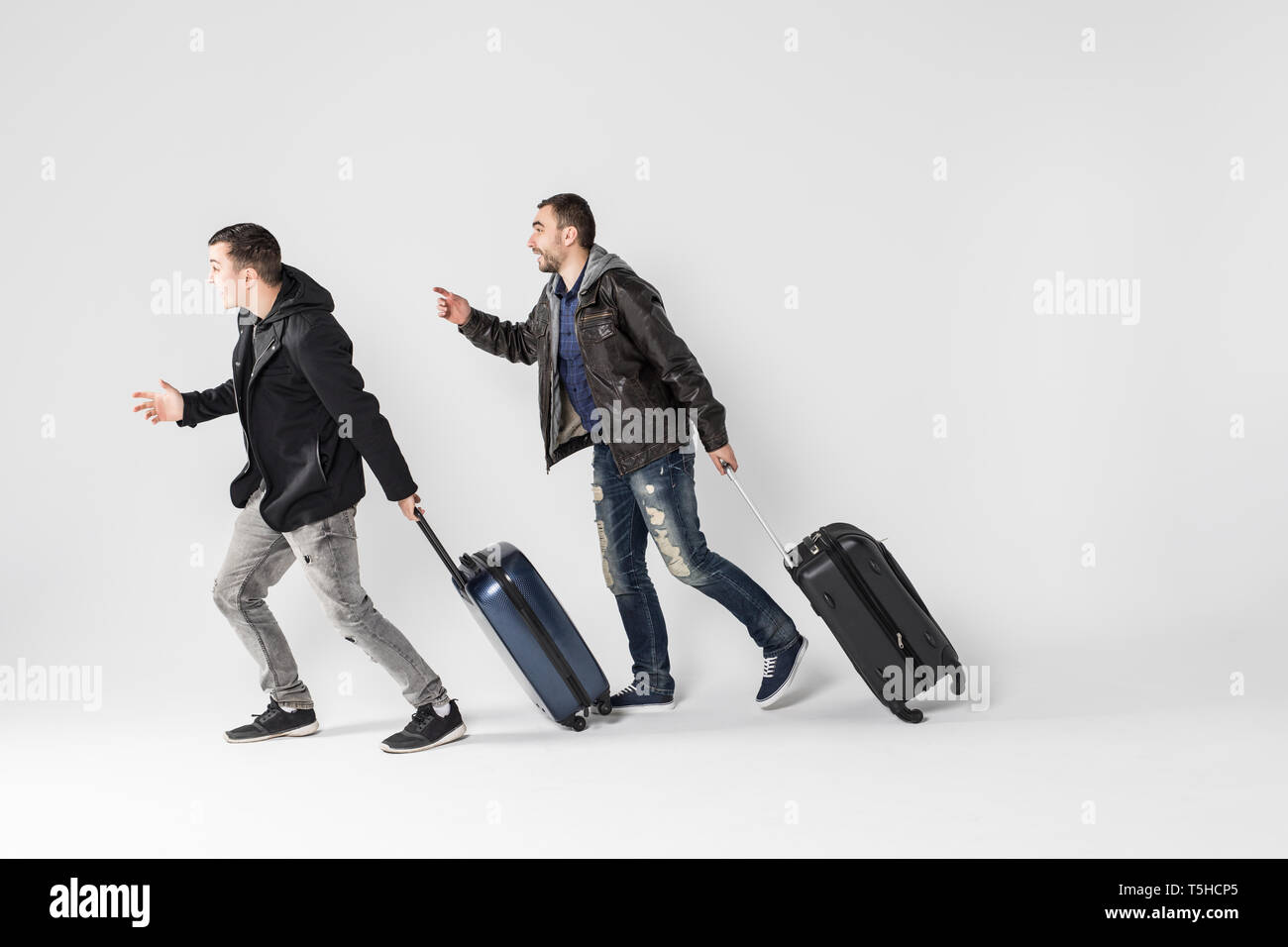 Two happy men friends running with baggage for travel with fun standing ...