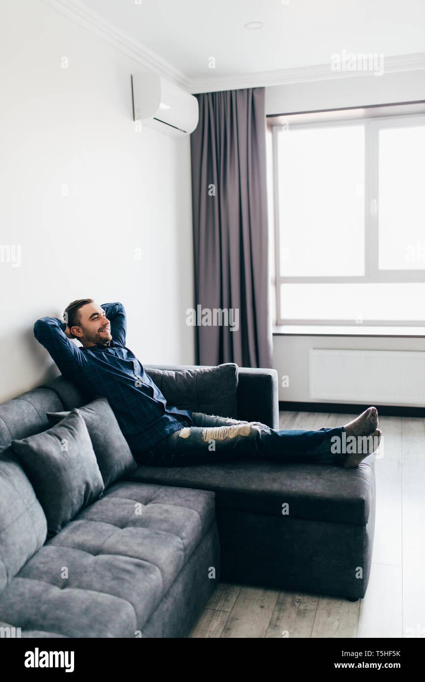 Young man sitting on coach rest at home Stock Photo - Alamy