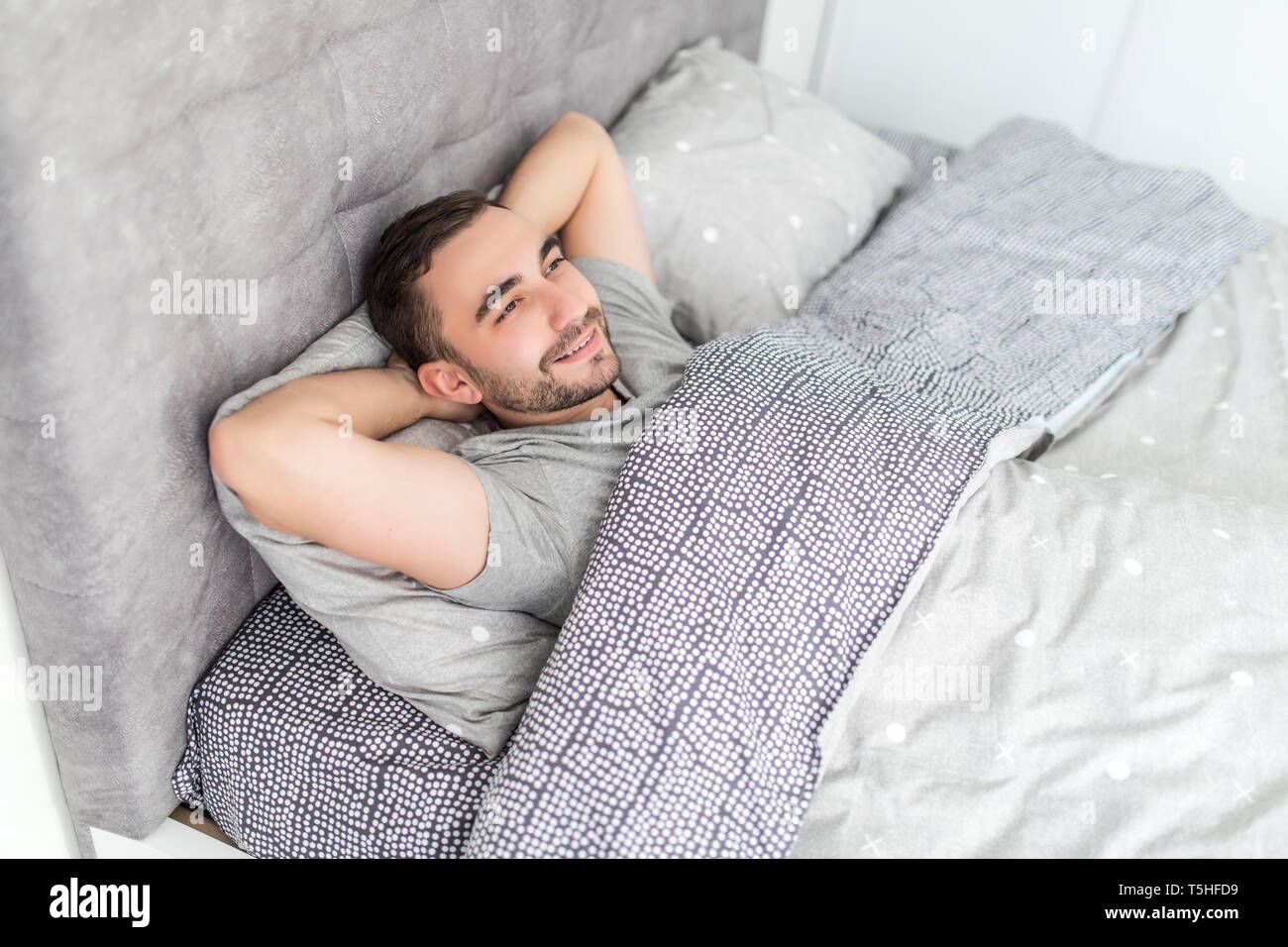 Handsome man lying in bed and looking at the camera Stock Photo - Alamy