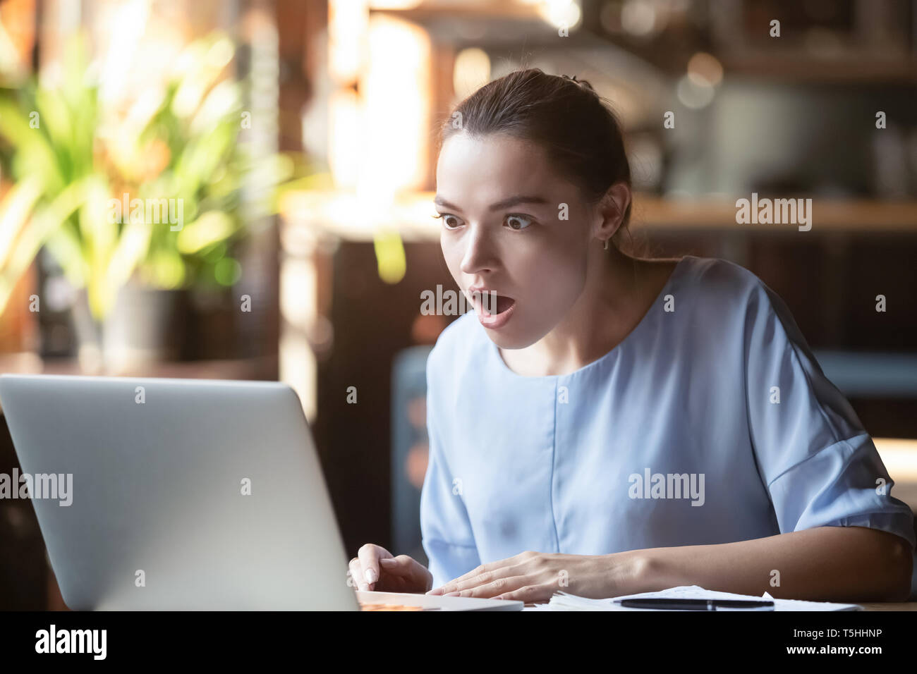 Female reading message on computer open mouth feels surprised amazed ...