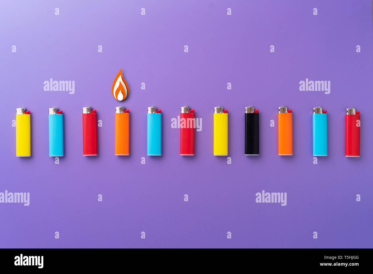 Multiple colorful lighters organized in a row over purple background ...