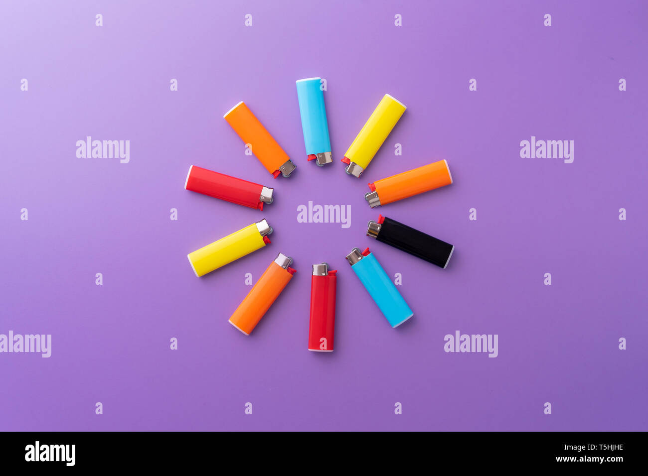 Multiple colorful lighters organized in a circle over purple background ...