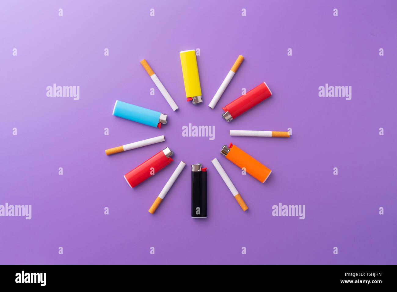 Multiple cigarettes and lighters organized in a circle over purple ...