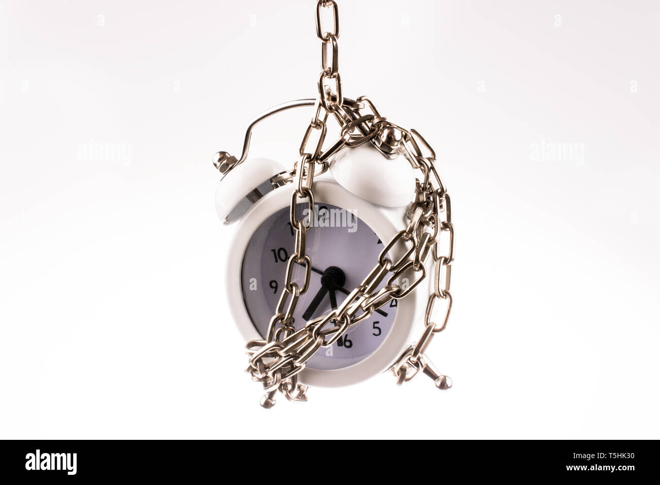 White color alarm clock in chain on a white background Stock Photo - Alamy