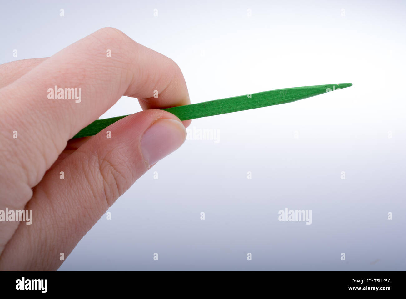 Little wooden sharp stick in hand on white background Stock Photo - Alamy