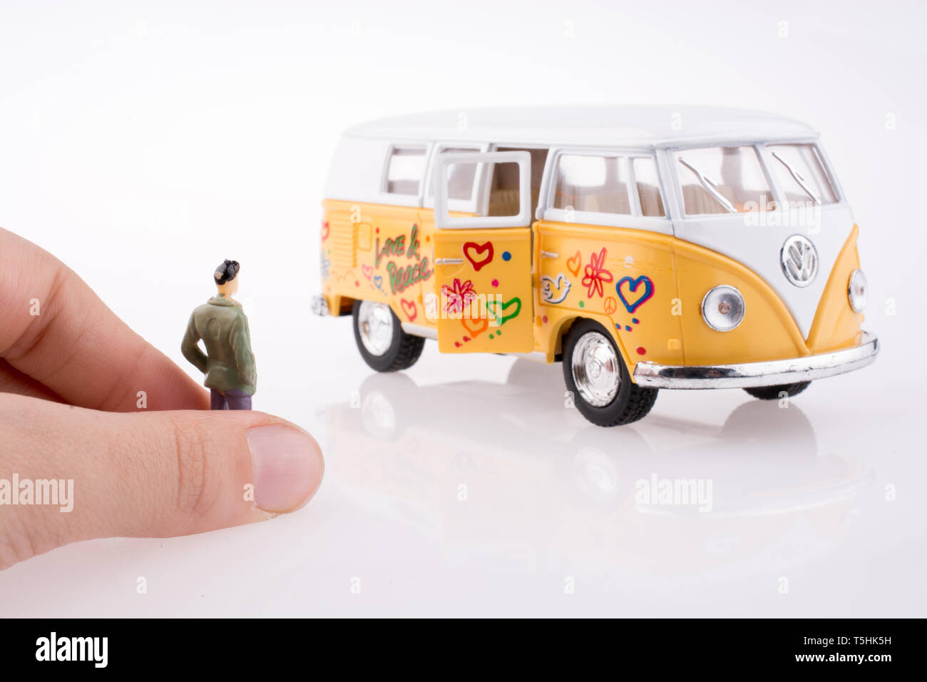 Hand holding a human figure near a peace van on a white background ...