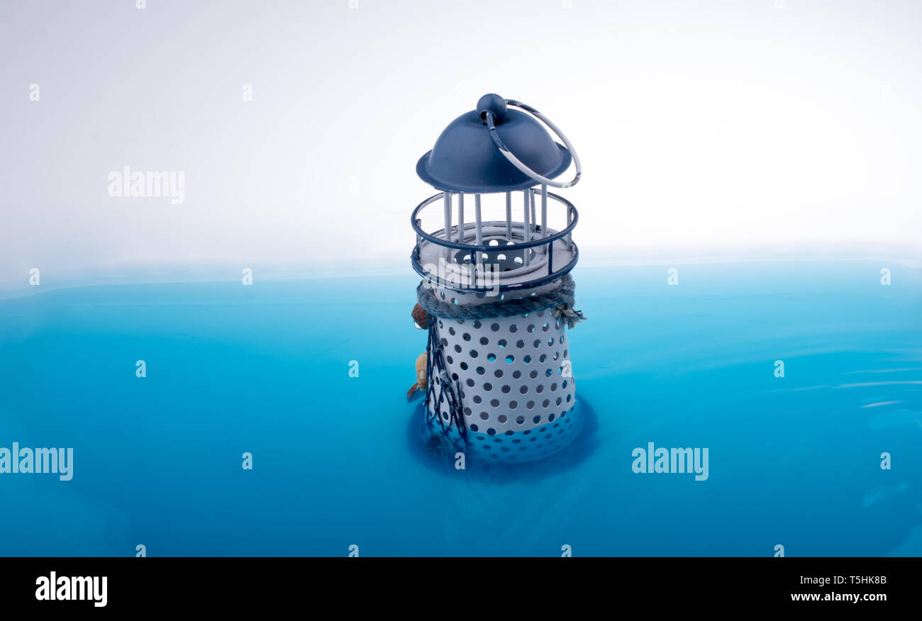 Little model lighthouse placed in blue water Stock Photo - Alamy