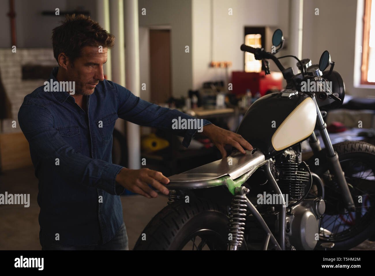 Bike mechanic fixing new seat in motorbike Stock Photo - Alamy