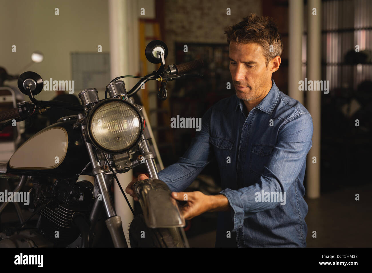 Bike mechanic repairing motorbike tire in garage Stock Photo - Alamy