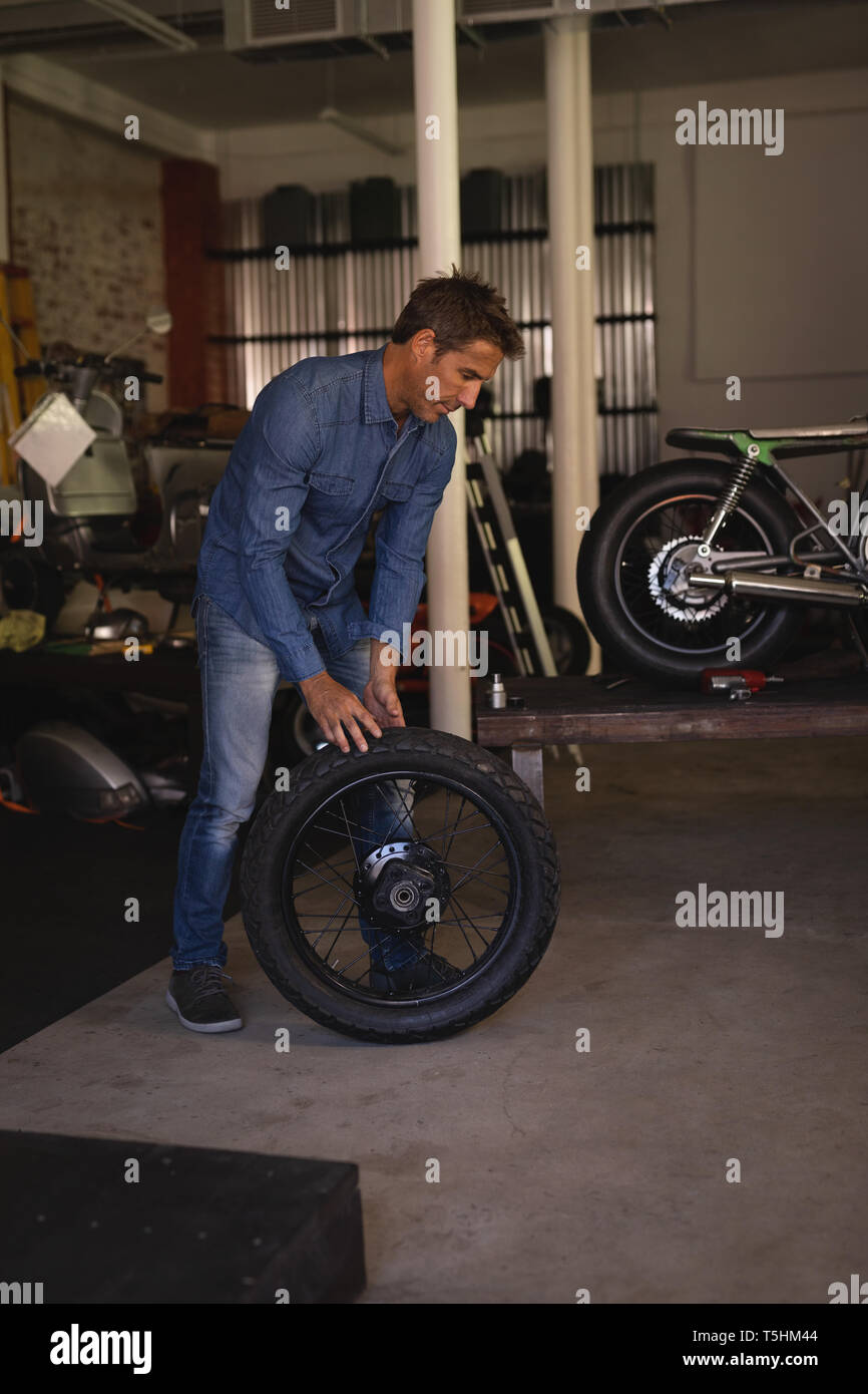 Mechanic holding tire in garage hi-res stock photography and images - Alamy