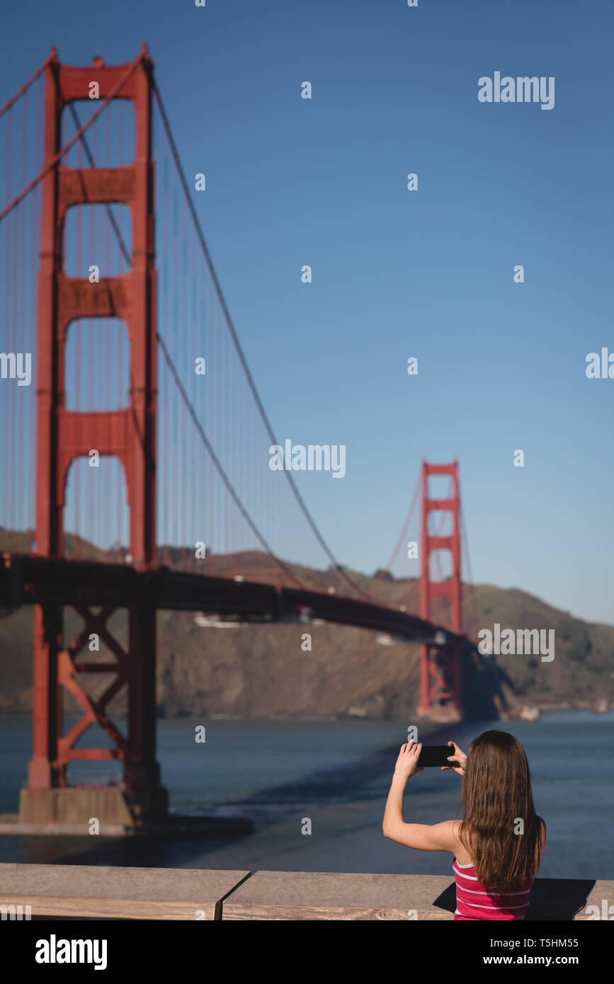 Woman taking picture with mobile phone of suspension bridge Stock Photo ...