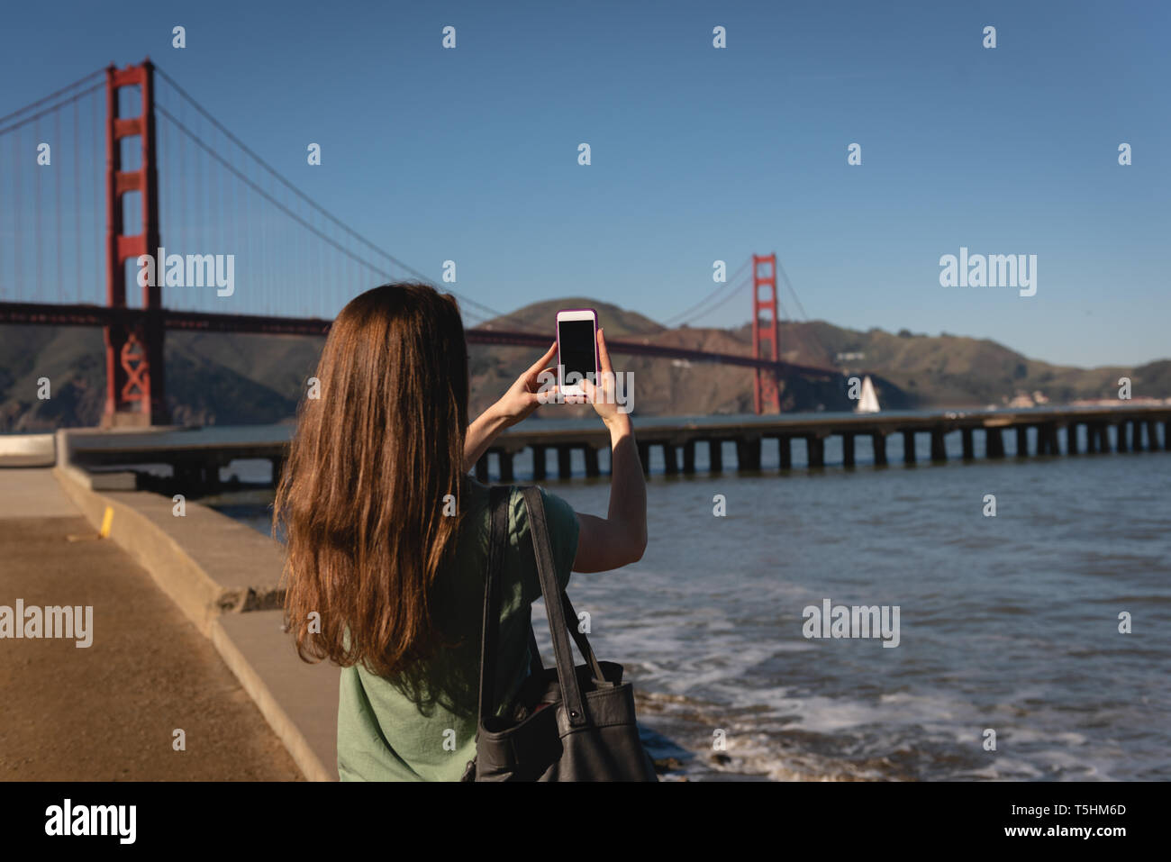 Woman capturing picture with mobile phone of suspension bridge Stock ...