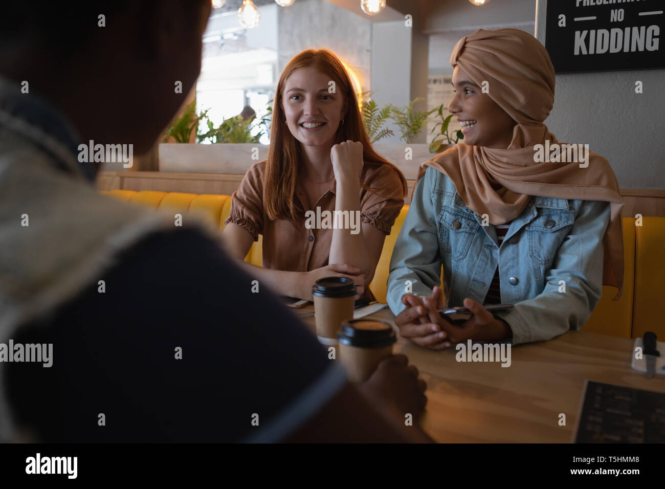 Female friends interacting with each other while having coffee Stock ...