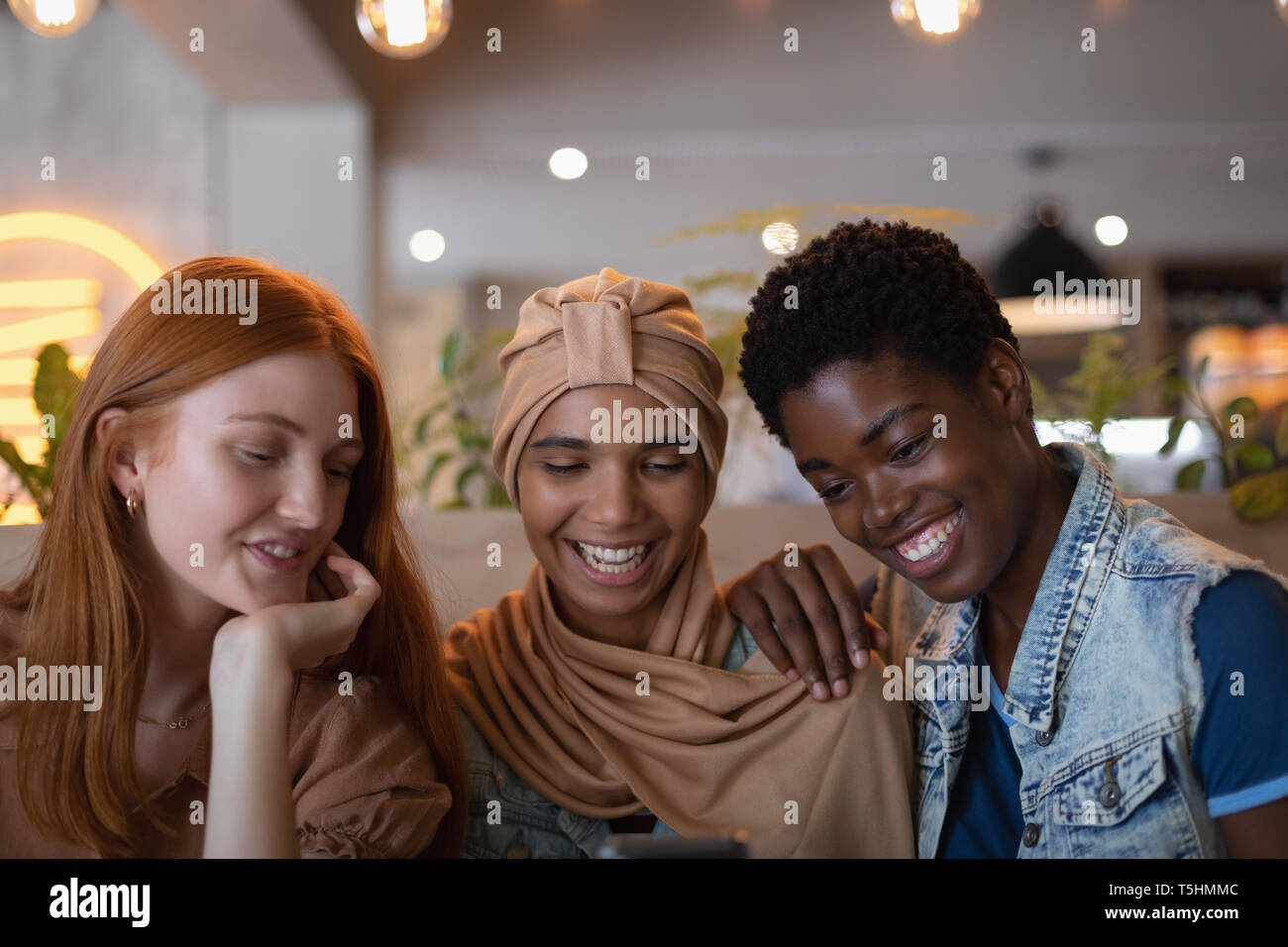 Female friends using mobile phone while sitting in the restaurant Stock ...