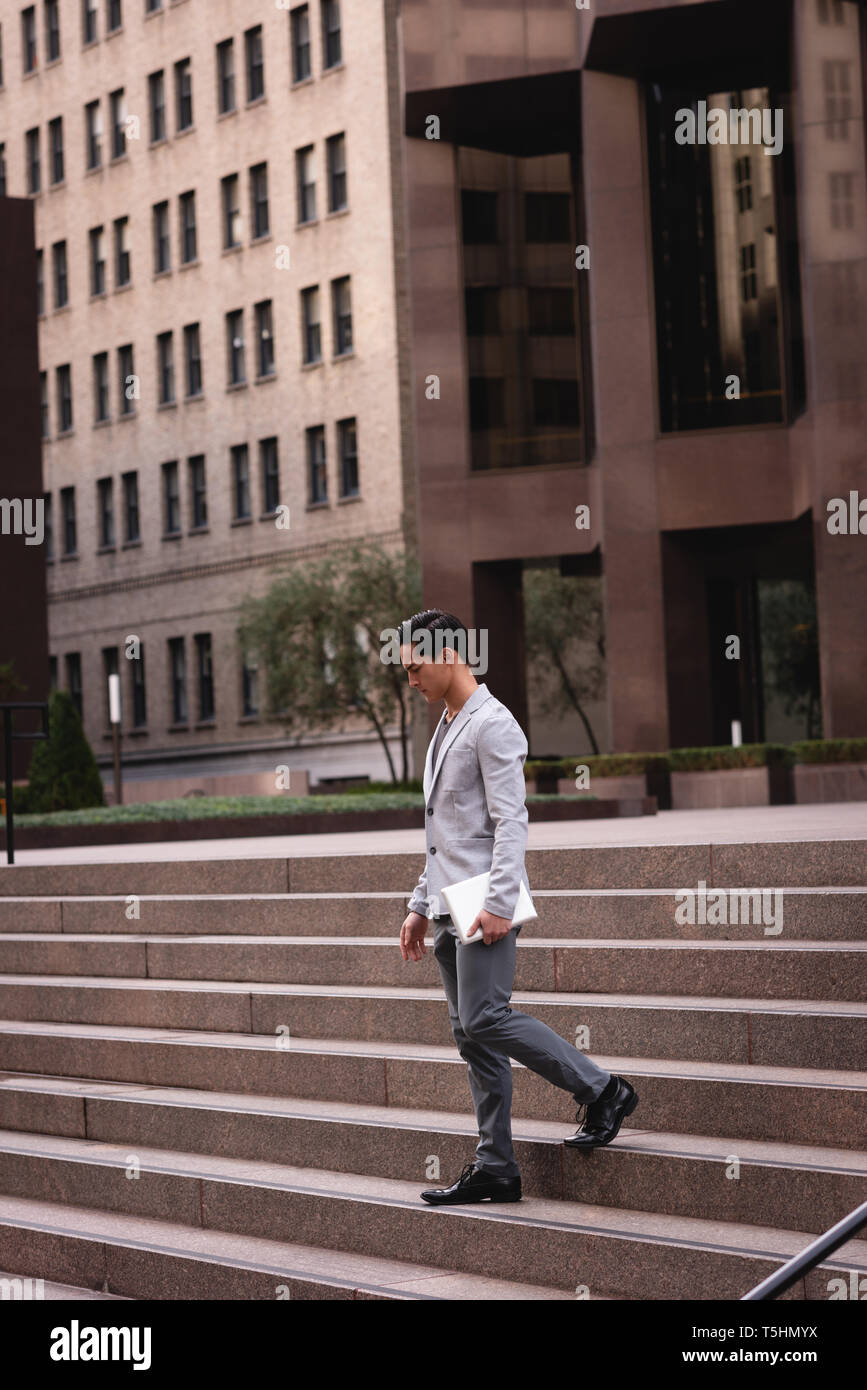 Handsome man walking from stair while holding digital tablet Stock ...