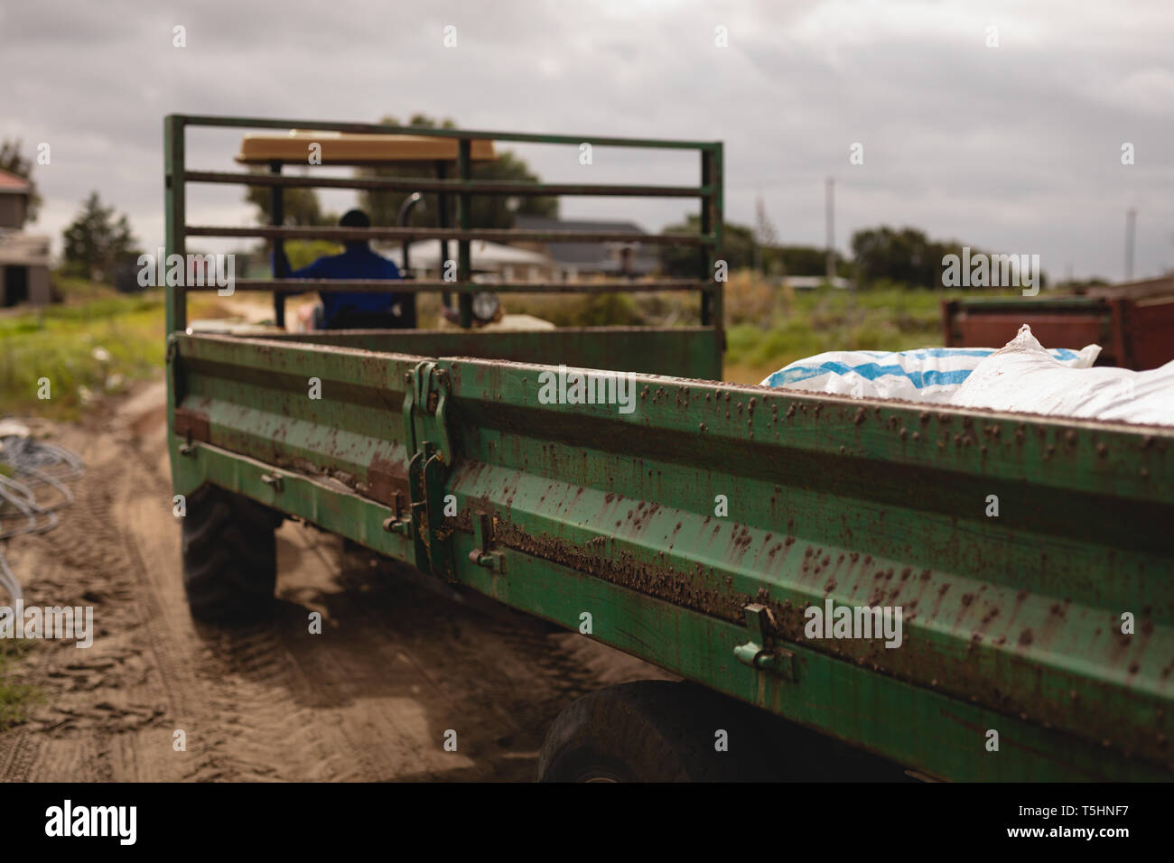 Male farmer driving tractor with loaded trailer Stock Photo - Alamy