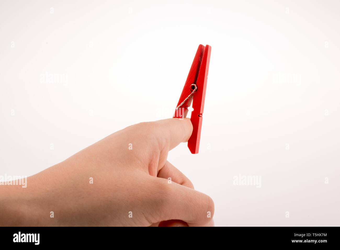 Hand holding a red clothespin on a white background Stock Photo - Alamy