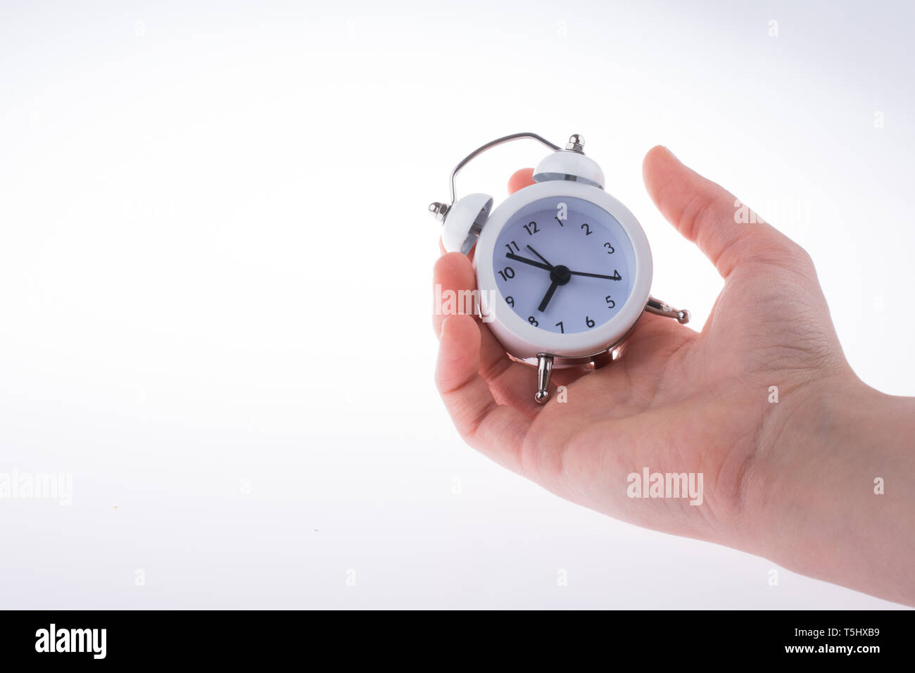 Alarm clock in hand on a white background Stock Photo - Alamy
