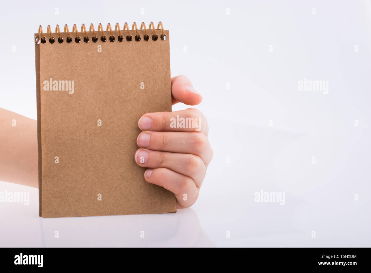 Hand holding a brown spiral notebook on a white background Stock Photo ...
