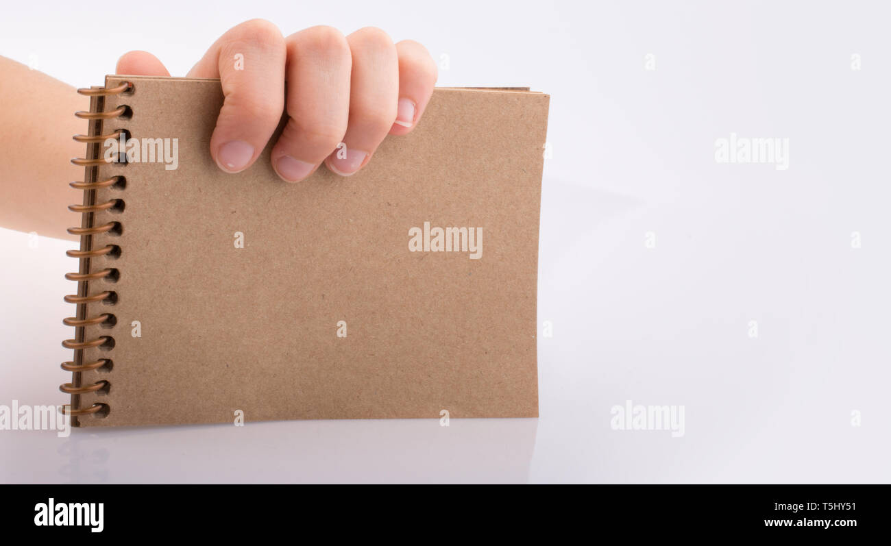 Hand holding brown color notebook on a white background Stock Photo - Alamy
