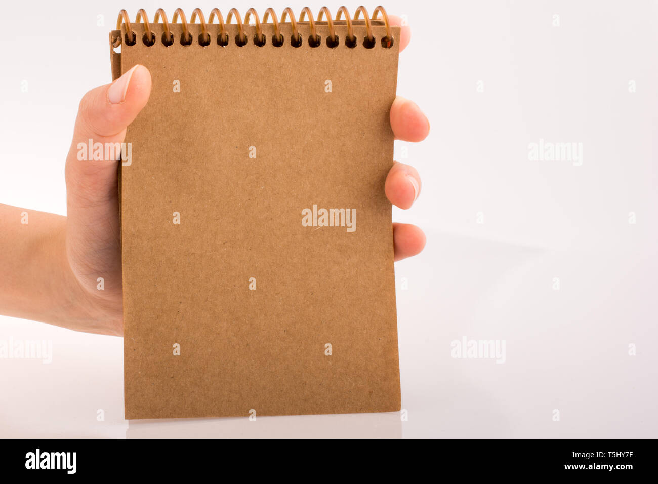 Hand holding a brown spiral notebook on a white background Stock Photo ...