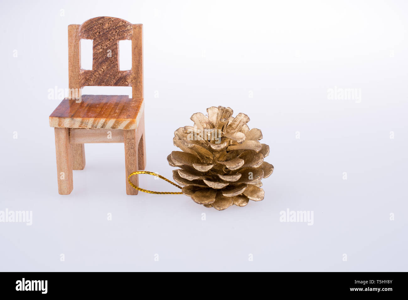 Pine cone bye the side of a model chair on a white background Stock ...