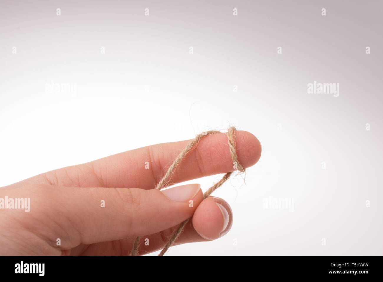 Hand holding linen thread on a white background Stock Photo - Alamy