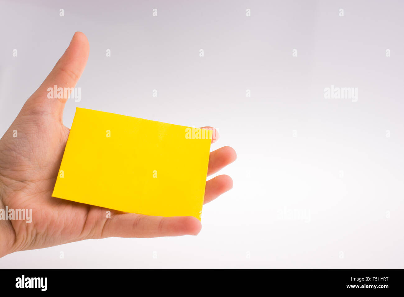 Hand holding yellow color rectangular paper on a white background Stock ...