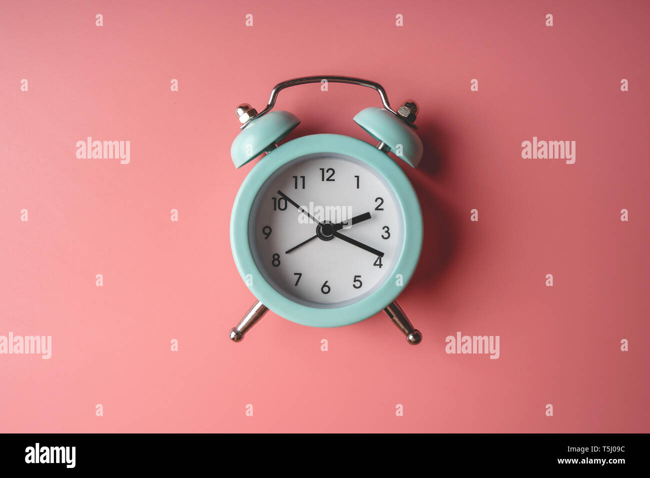 Blue analog metal alarm clock on stylish blue-pink background. The ...