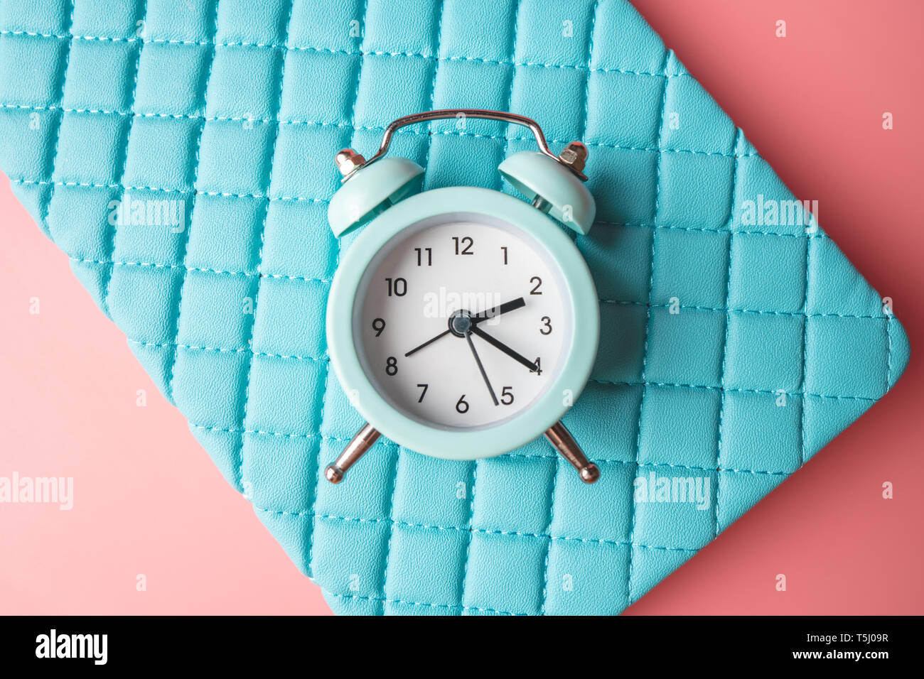 Blue analog metal alarm clock on stylish blue-pink background. The ...