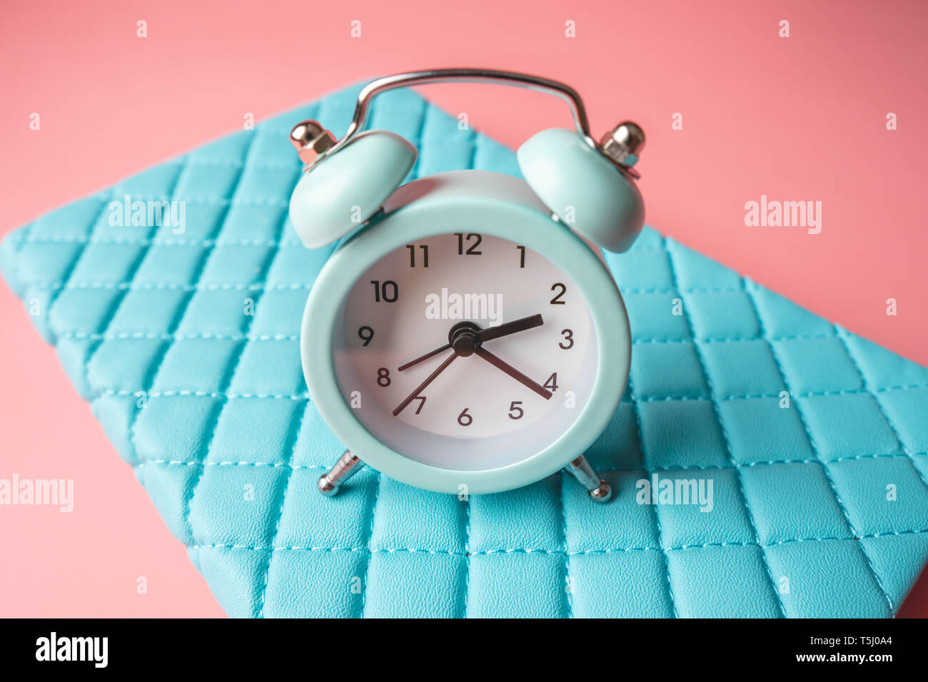 Blue analog metal alarm clock on stylish blue-pink background. The ...