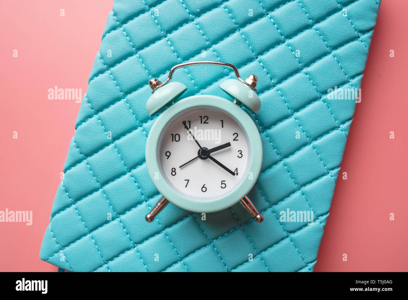 Blue analog metal alarm clock on stylish blue-pink background. The ...