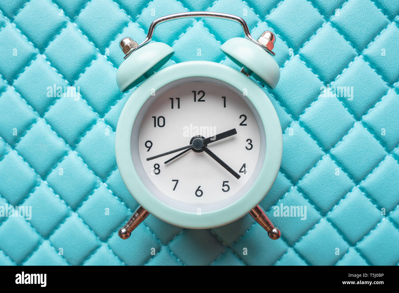 Blue analog metal alarm clock on stylish blue-pink background. The ...