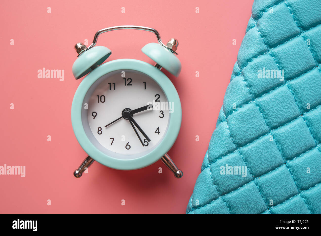 Blue analog metal alarm clock on stylish blue-pink background. The ...