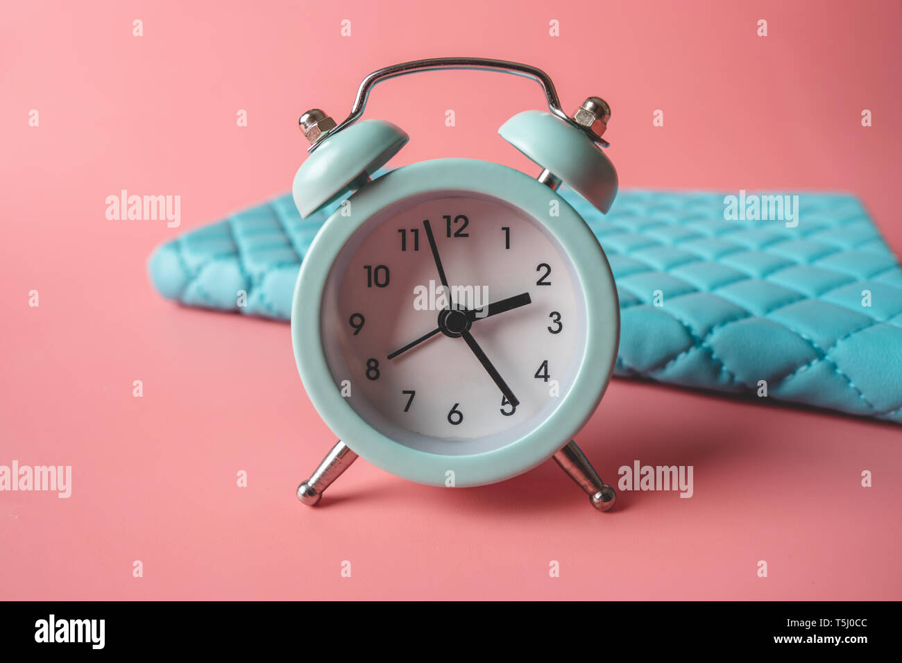 Blue analog metal alarm clock on stylish blue-pink background. The ...
