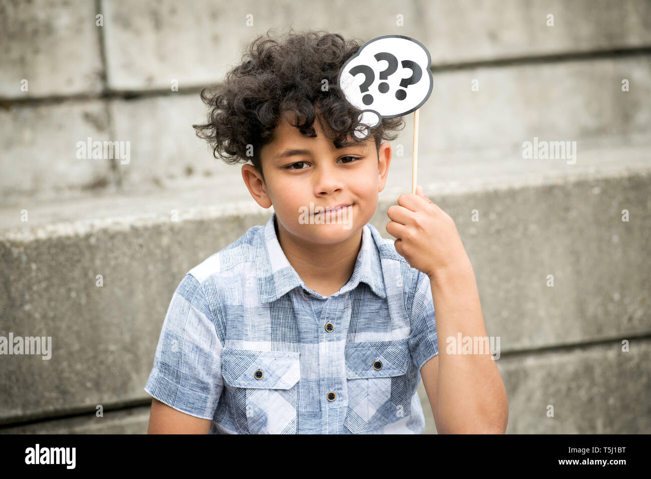 Confused young boy sitting thinking deeply with question marks on a ...