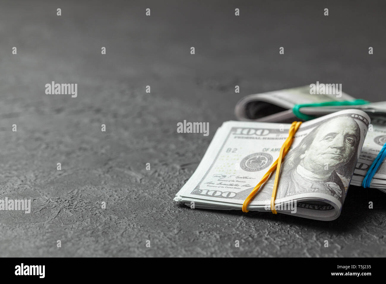 Stacks of cash dollars tied with colored office bands on dark ...
