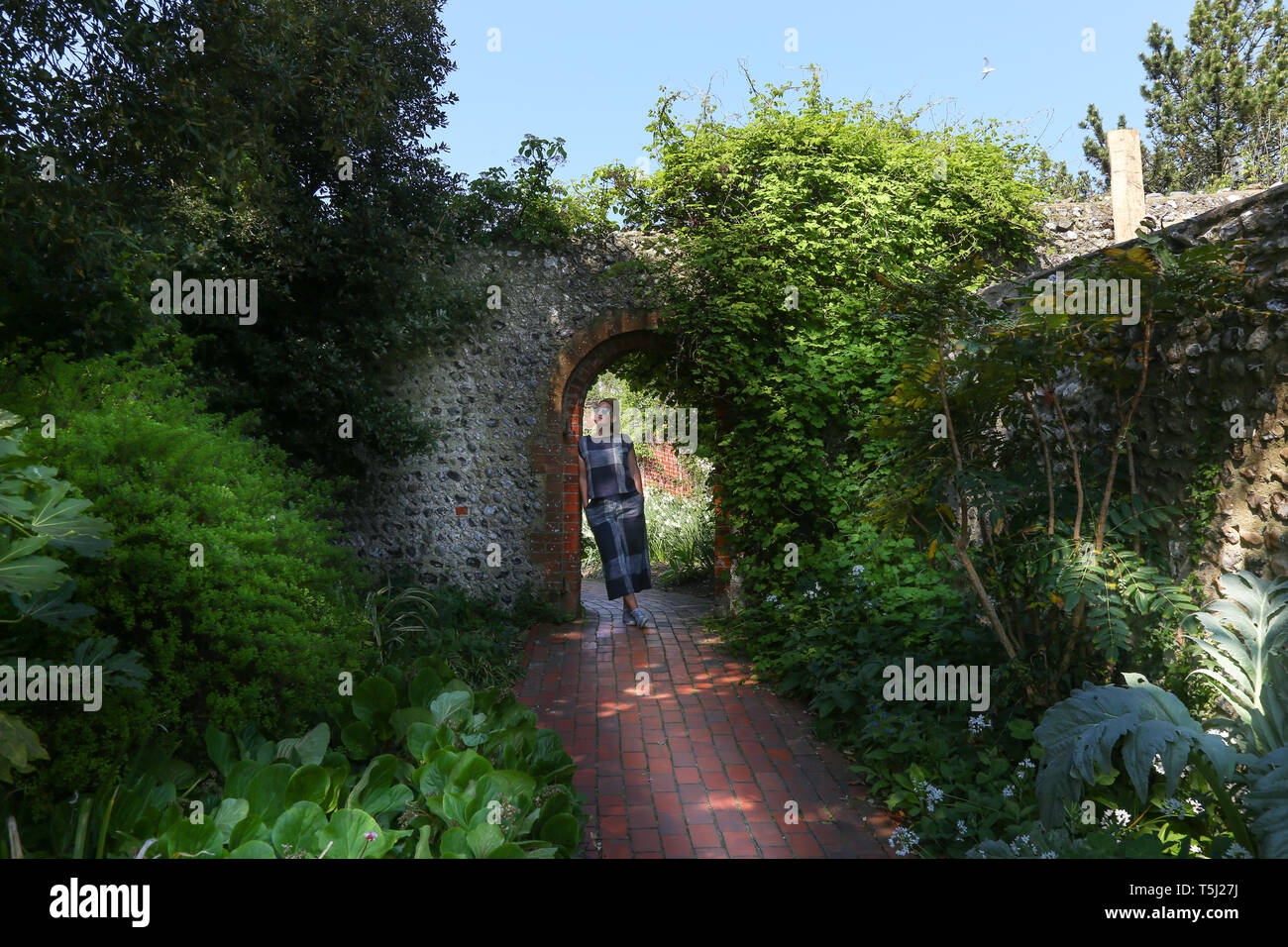 a young woman standing inside a brick arch in the Kipling gardens ...