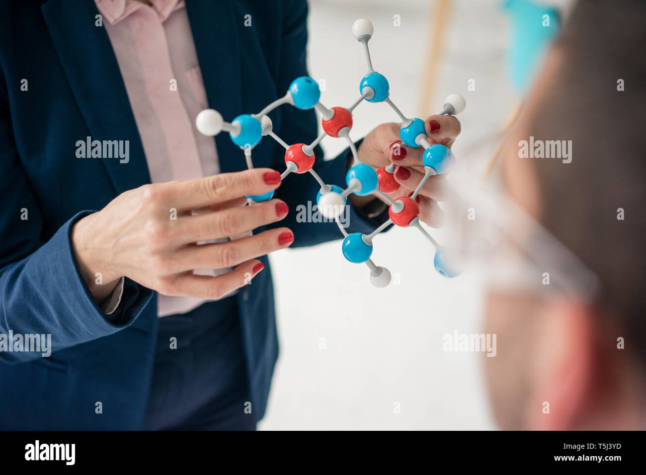 Businesswoman holding molecule model, teaching teenage boy Stock Photo ...