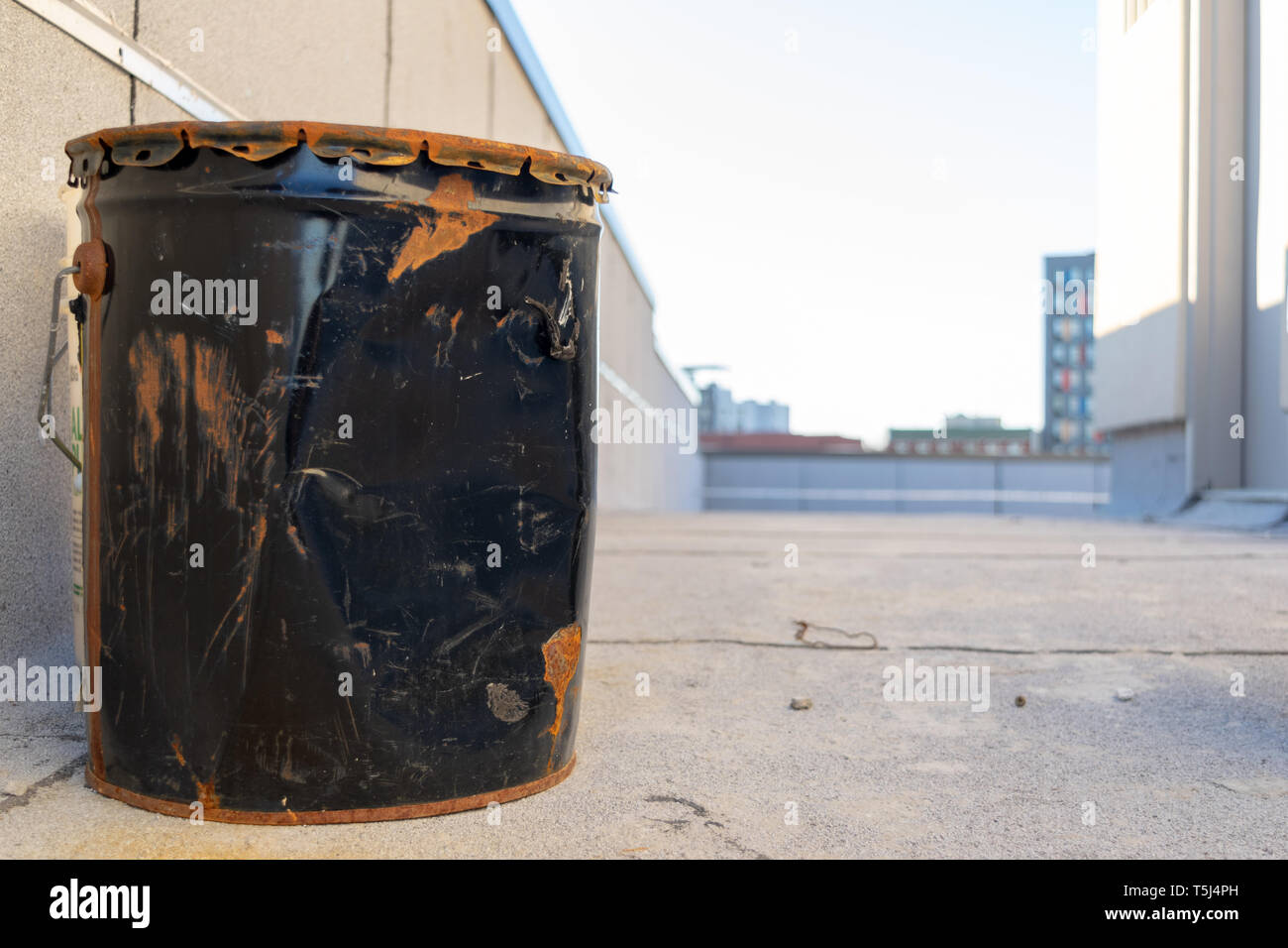Old, black metal bucket, dented and rusty, on a New York City rooftop ...